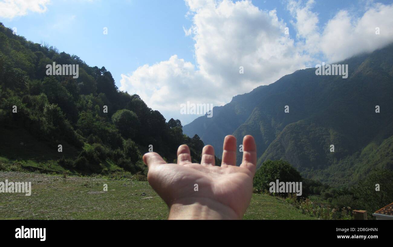 Close up young male, man hand showing big green Caucasian mountains and ...