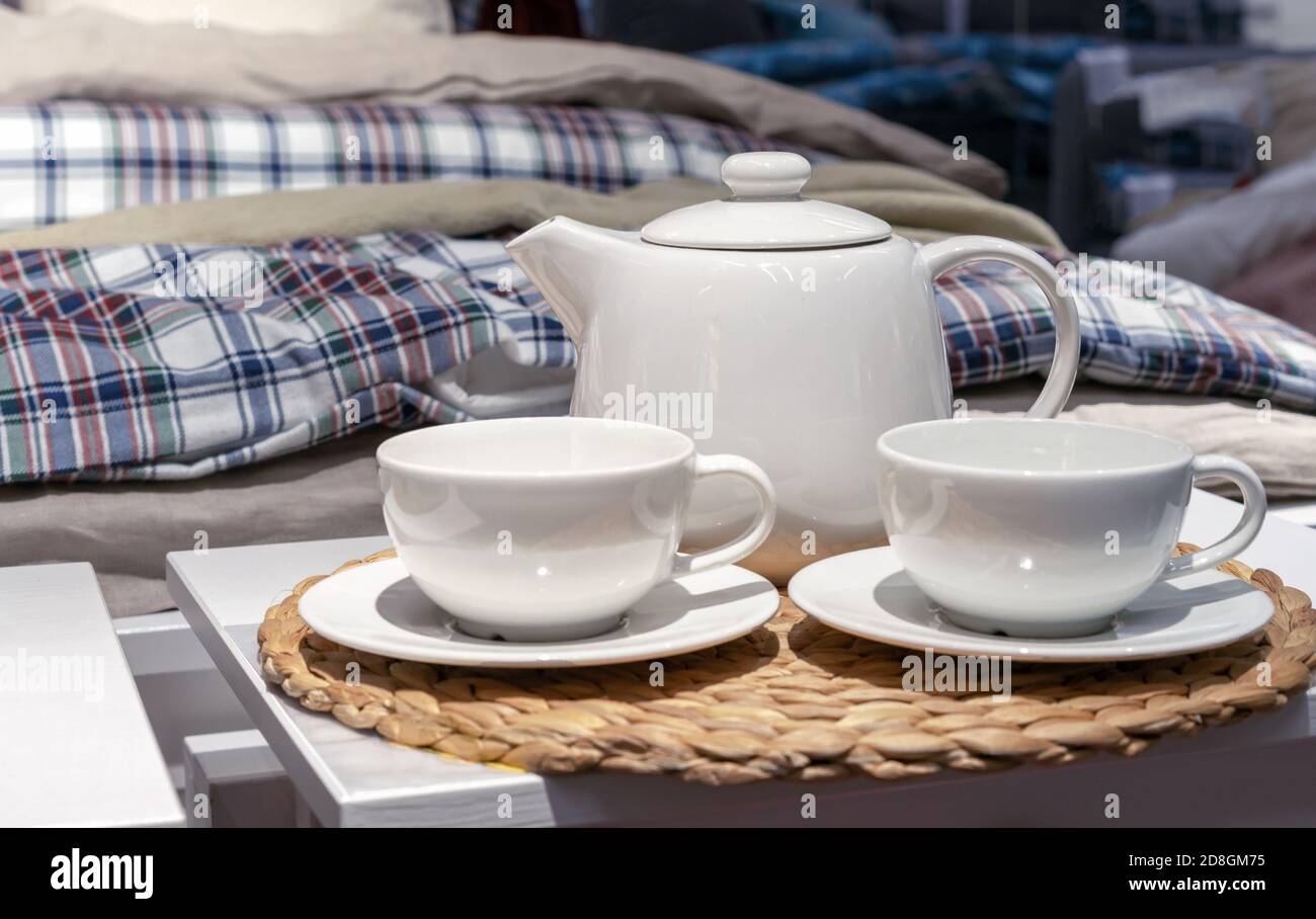White ceramic teapot and tea cups on the bedside table in the bedroom ...