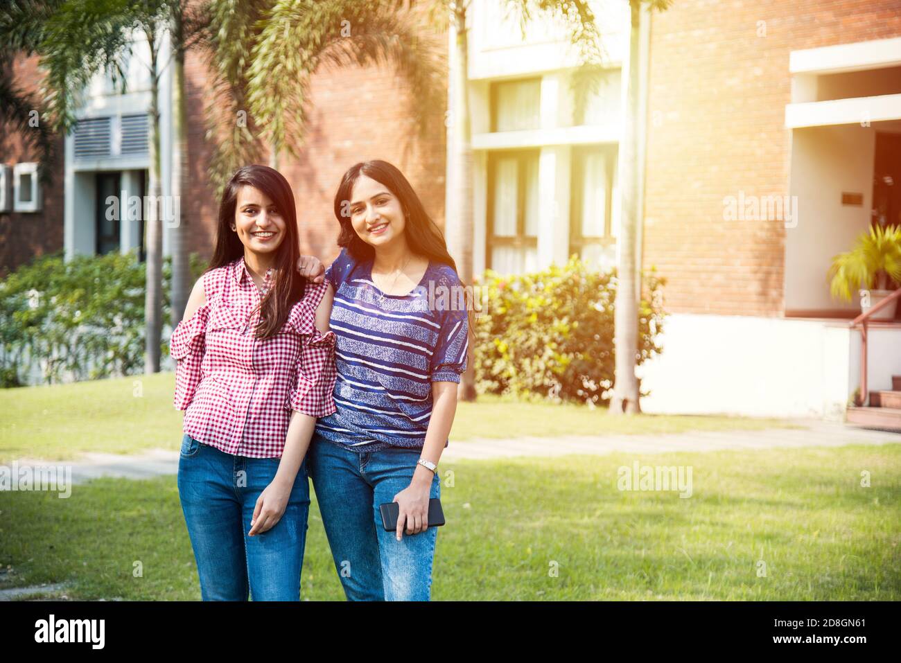 Two Indian asian collage girl students or friends posing for photograph ...