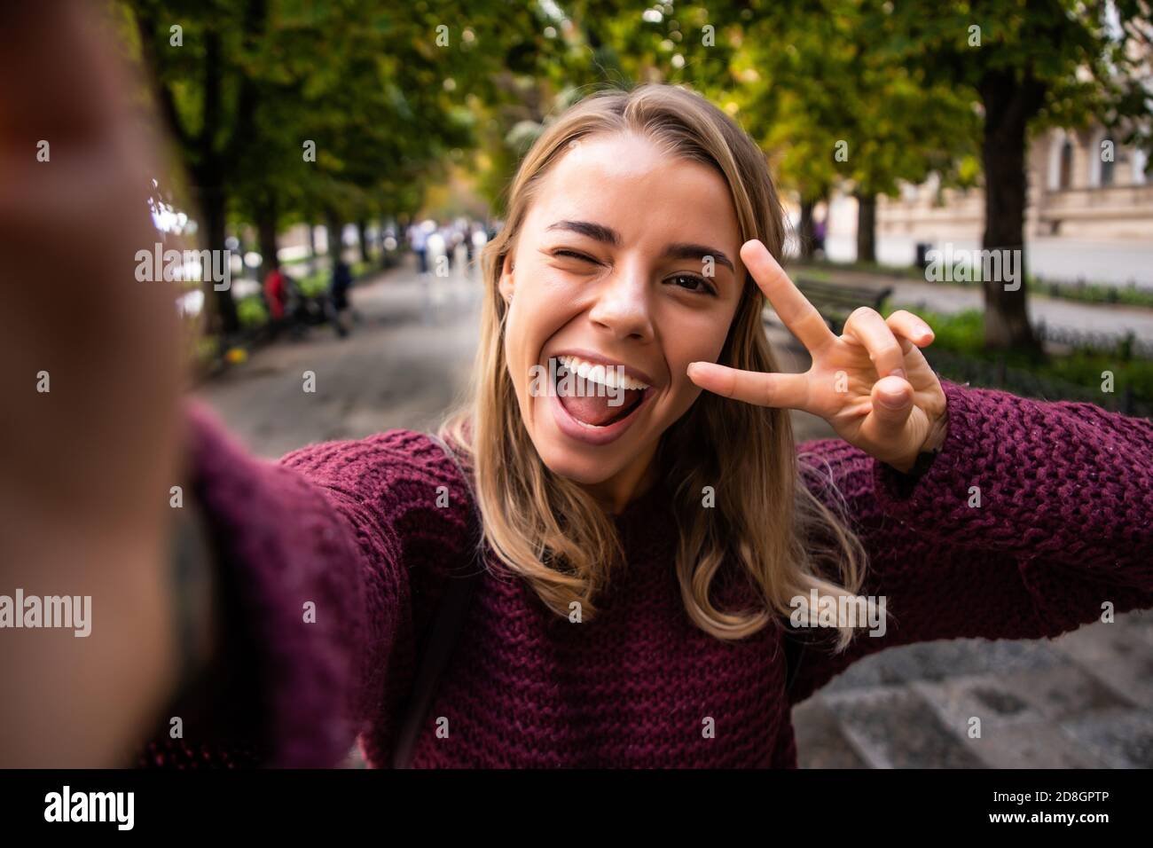 young attractive cheerful girl takes a selfie and makes peace sign with ...