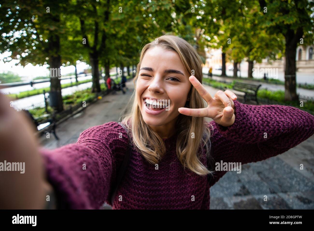young attractive cheerful girl takes a selfie and makes peace sign with ...