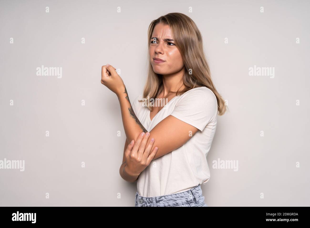 Beautiful woman holding her elbow with pain and arm ache on white ...
