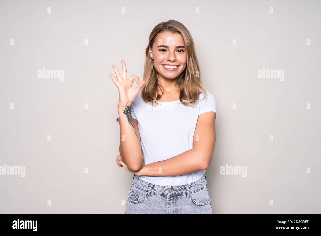 Happy smiling young woman showing okay gesture isolated over white ...