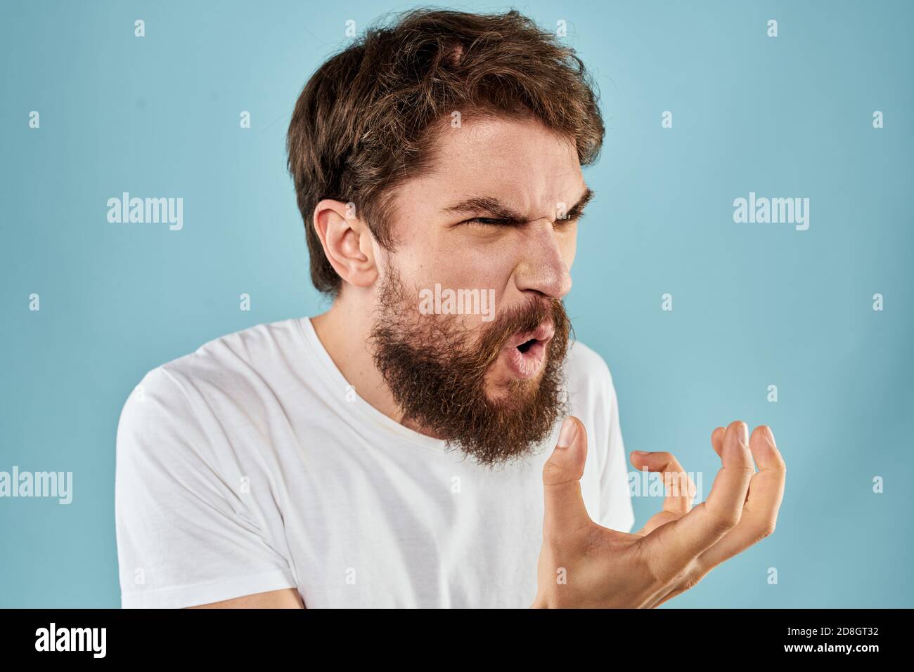 Bearded man in white T-shirt emotions gestures with hands displeased ...