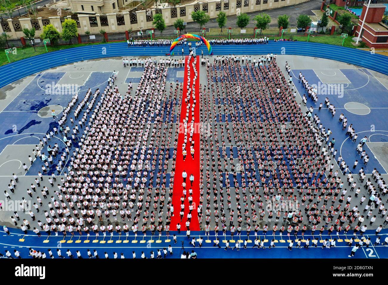 An aerial view of students arraying on the playground, attending a ...