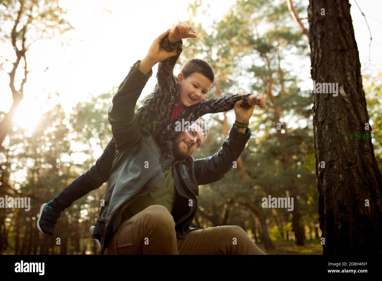 Piggyback. Father and son walking and having fun in autumn forest, look ...