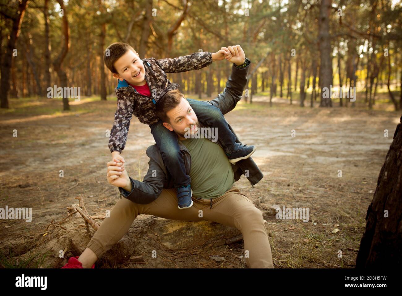 Piggyback. Father and son walking and having fun in autumn forest, look ...