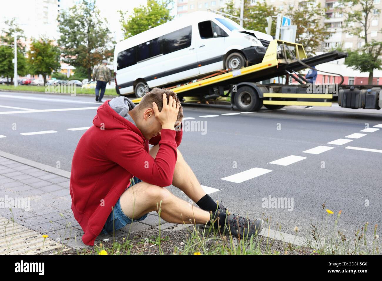 Minivan driver sits on side of road and holds his head during ...