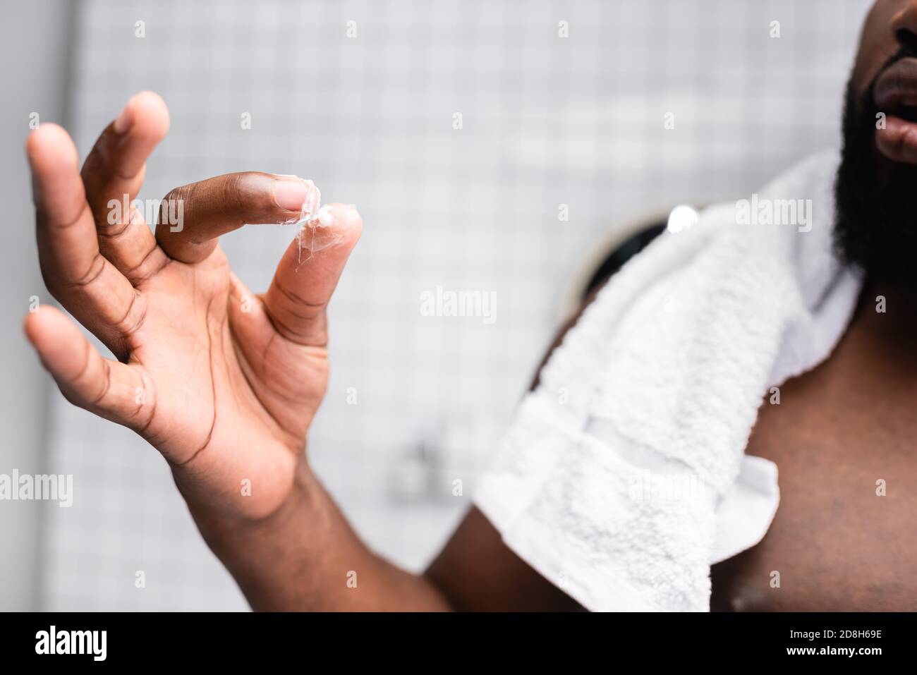 partial view of afro-american man using cure for strengthening beard ...