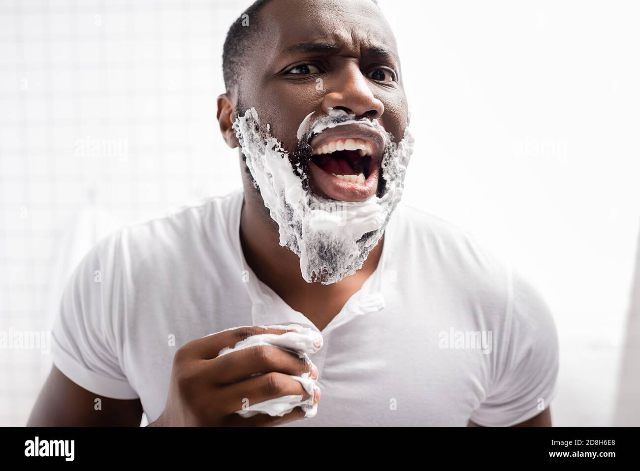 afro-american man applying shaving foam with open mouth Stock Photo - Alamy