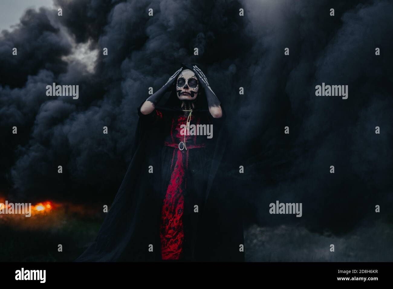 Young woman stands in Halloween costume of death with painted skeleton ...