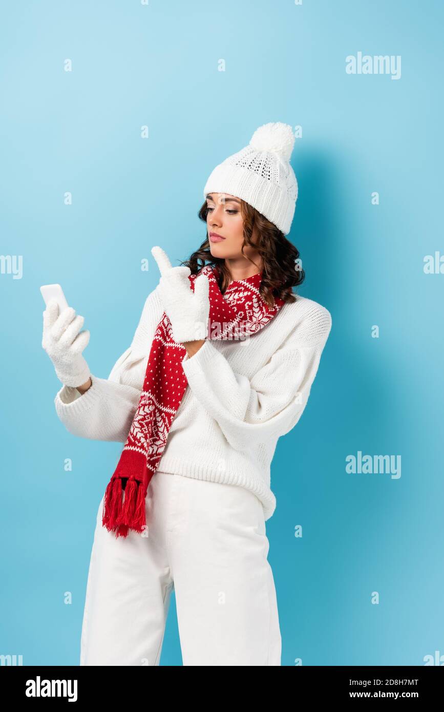 young woman in white winter outfit showing middle finger to smartphone ...