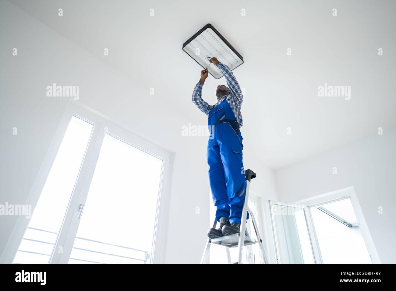 African Maintenance Electrician On Ladder Fixing And Installing Light ...