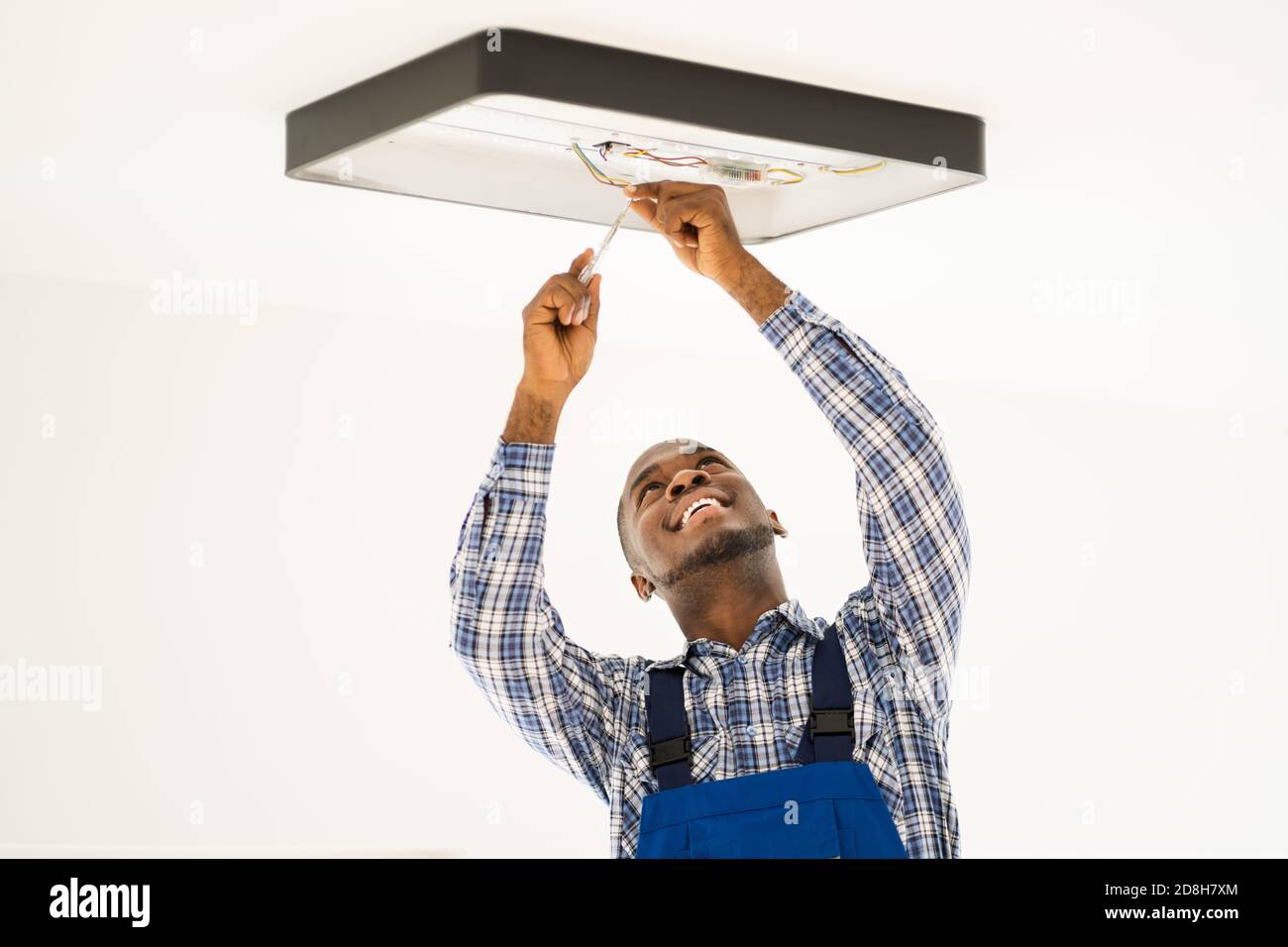 African Maintenance Electrician On Ladder Fixing And Installing Light ...