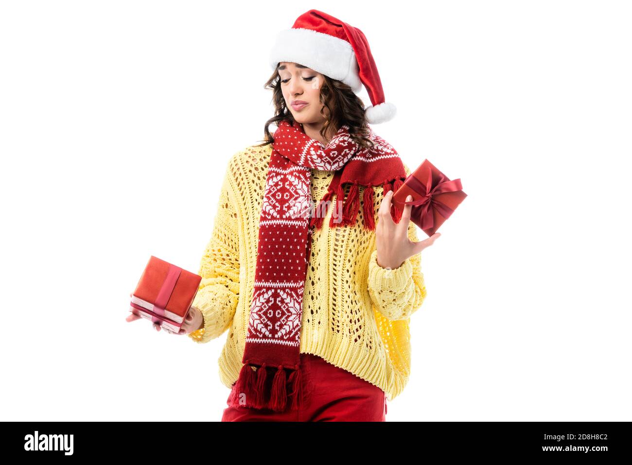 skeptical woman in santa hat and red scarf holding presents isolated on ...