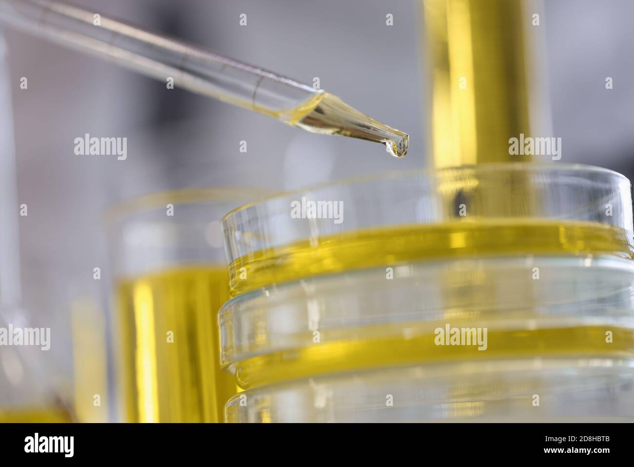 Drop of yellow liquid flows out of glass pipette in chemical laboratory ...