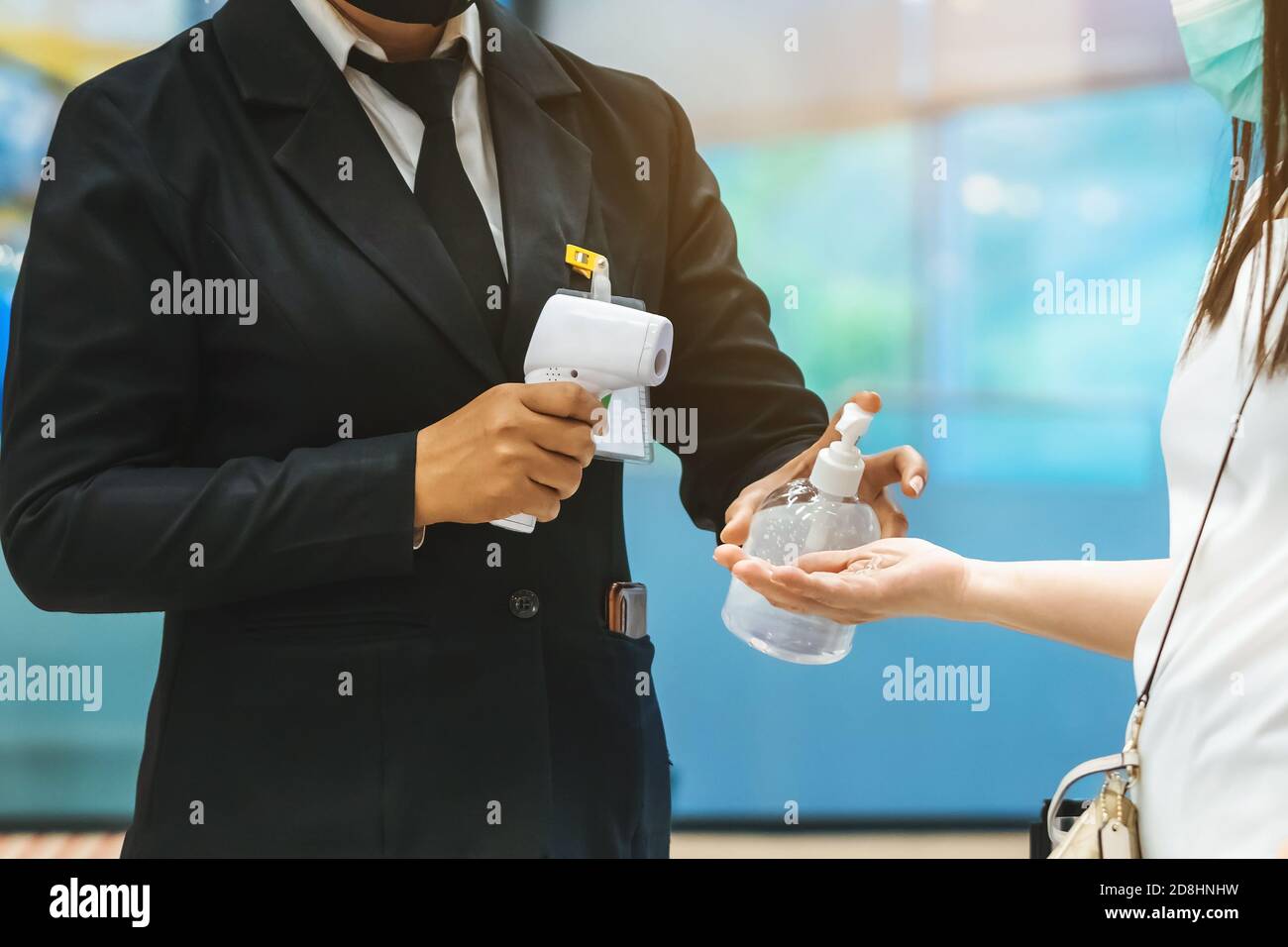 Hand of customer waits for a drop of alcohol gel from female security ...