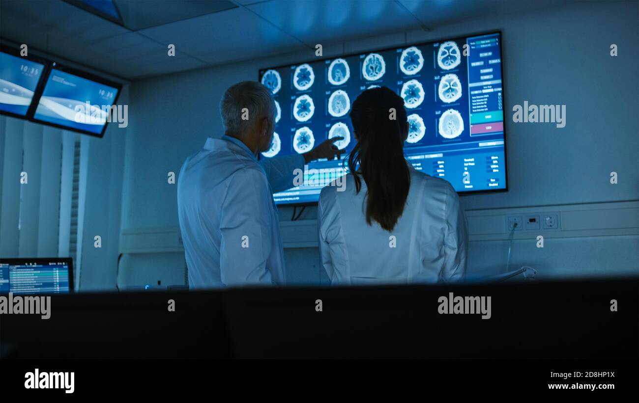 Two Medical Scientists Neurologists, Talking and Pointing at Wall TV ...