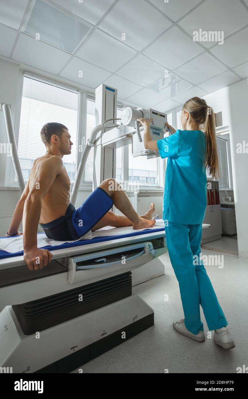 In the Hospital, Man Sitting on a Bed, Female Technician adjusts X-Ray ...