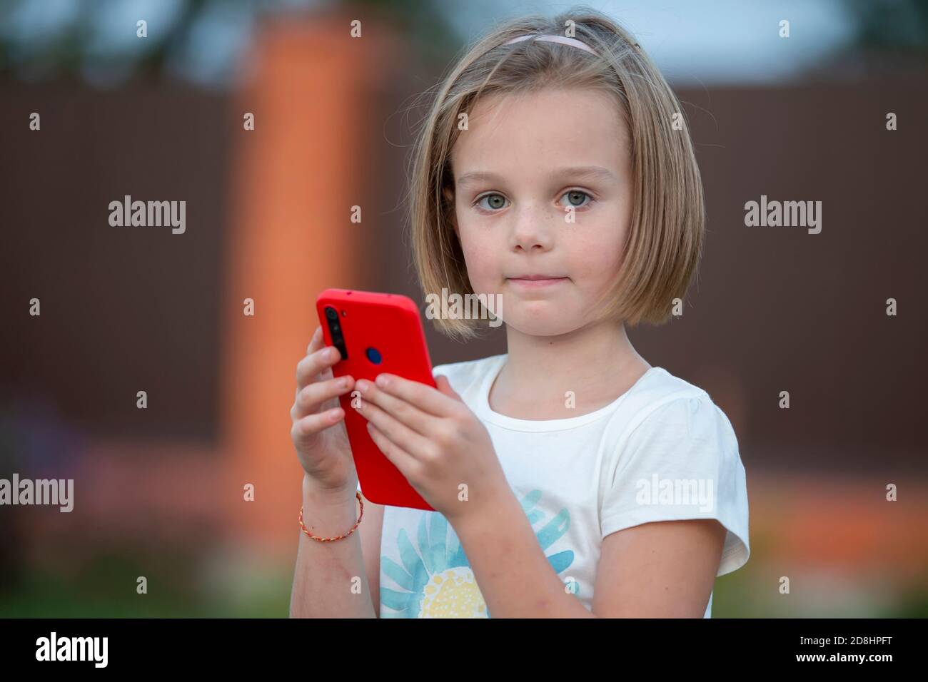 Child with a smartphone. Funny little girl with a red phone Stock Photo ...