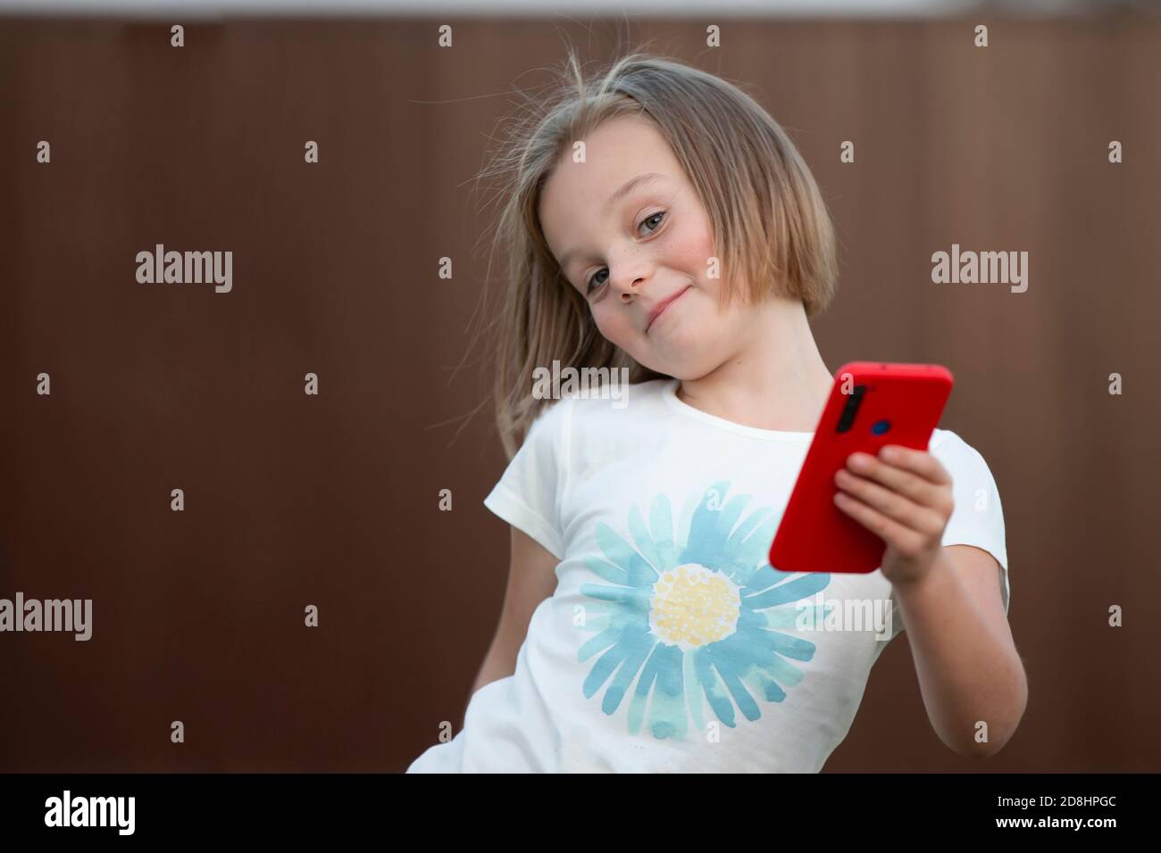 Child with a smartphone. Funny little girl dancing with a red phone ...