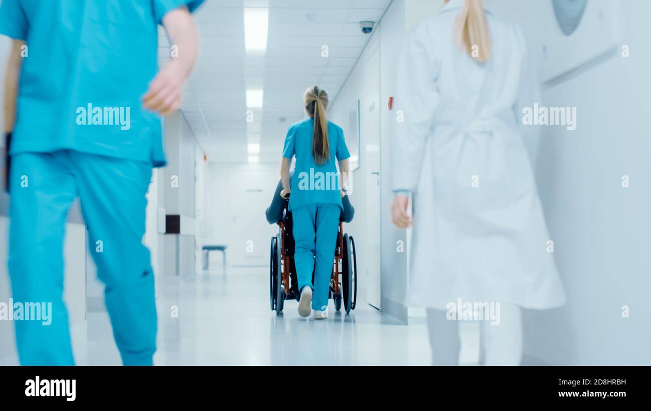 Shot of the Female Nurse Moving Patient in the Wheelchair Through the ...