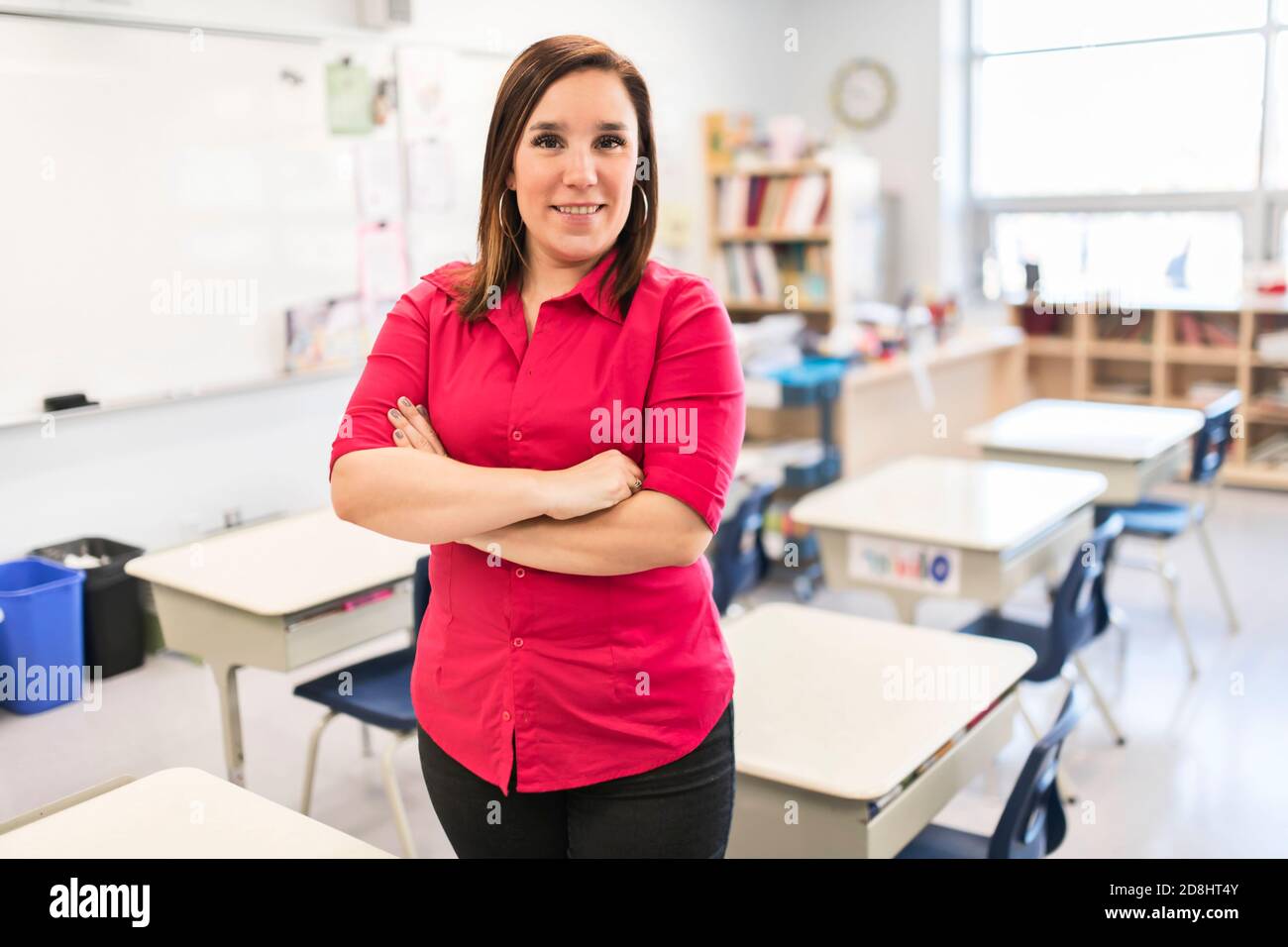 A Pretty teacher smiling at camera at back of classroom at the ...