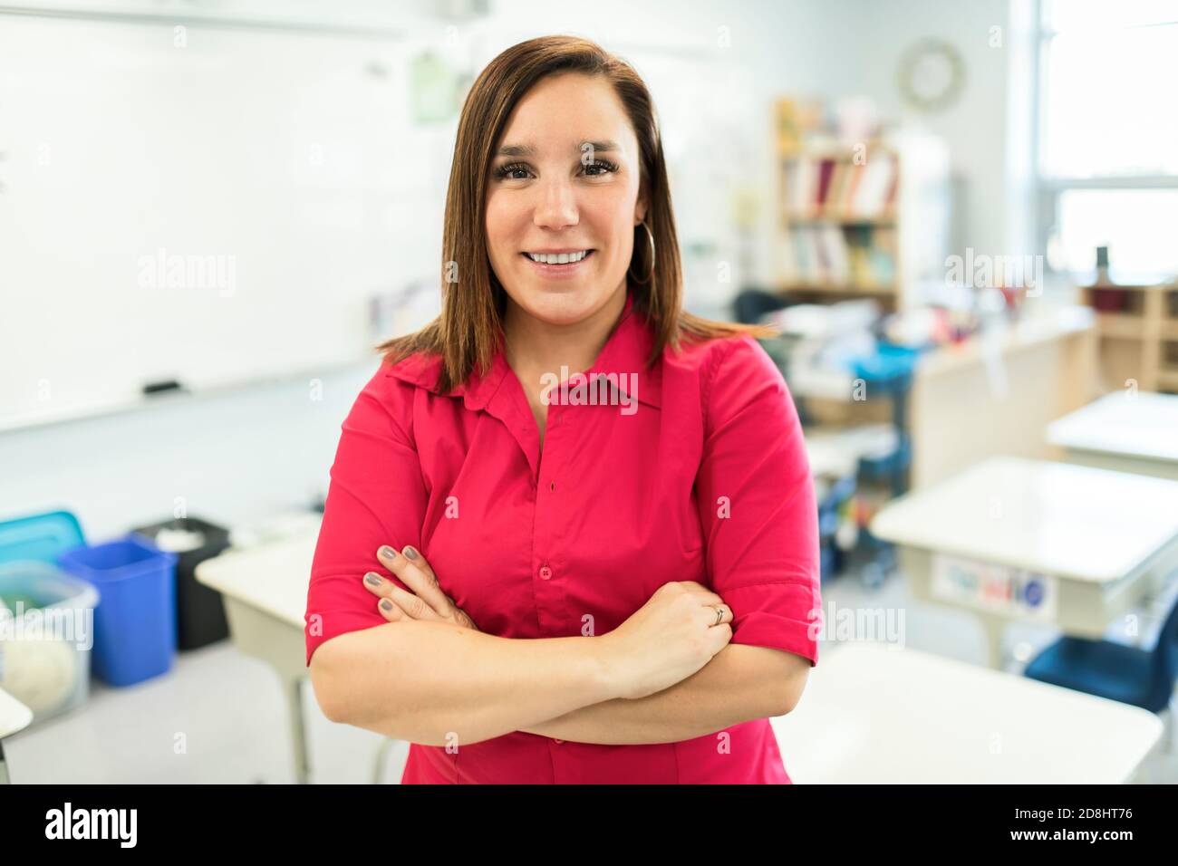 A Pretty teacher smiling at camera at back of classroom at the ...