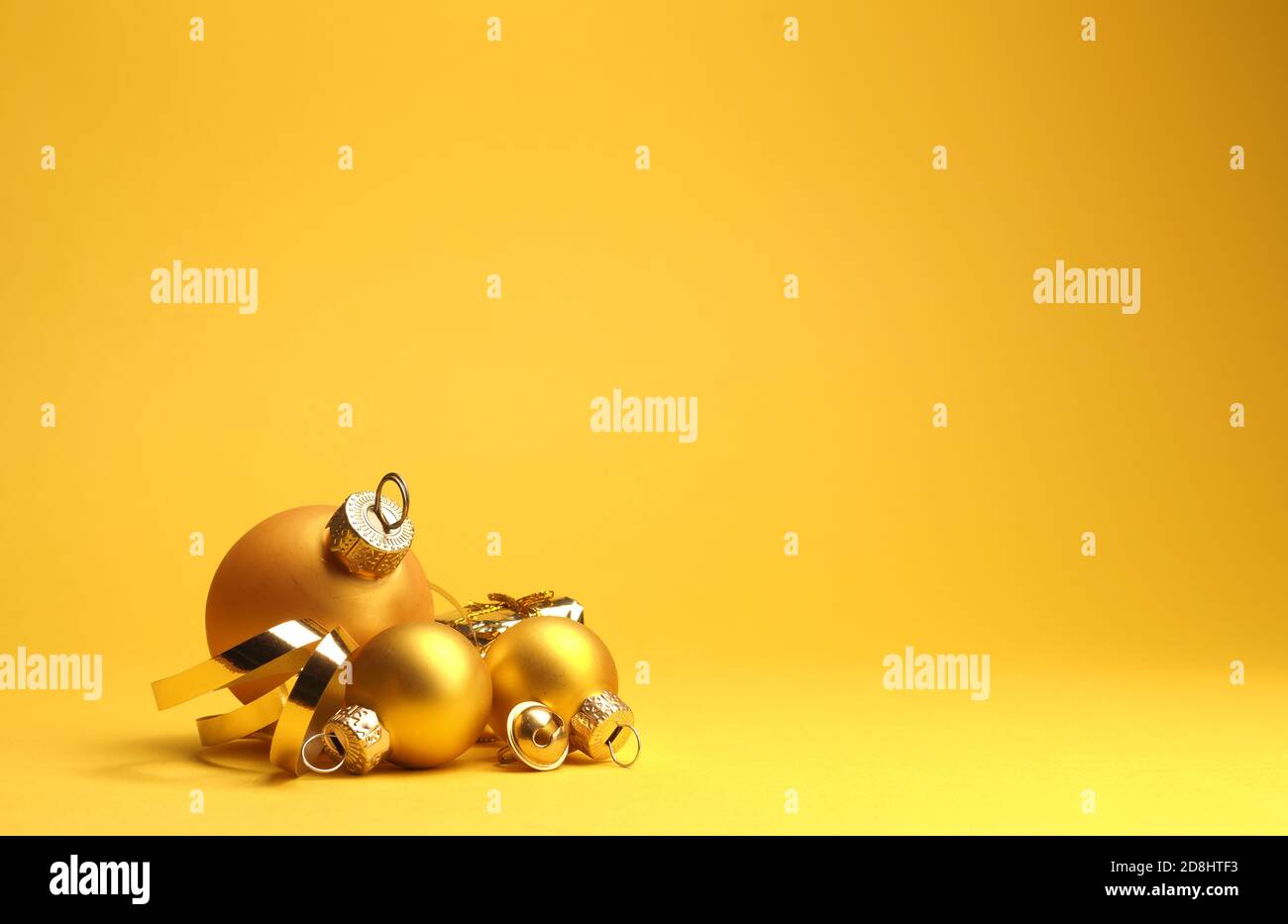 Three golden vintage Christmas baubles on a yellow background with ...