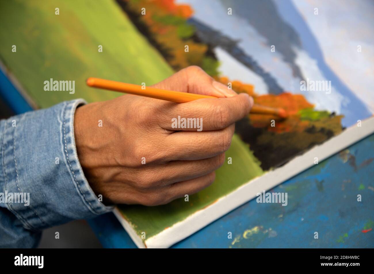 A student artist using her paintbrush, painting a picture using acrylic ...