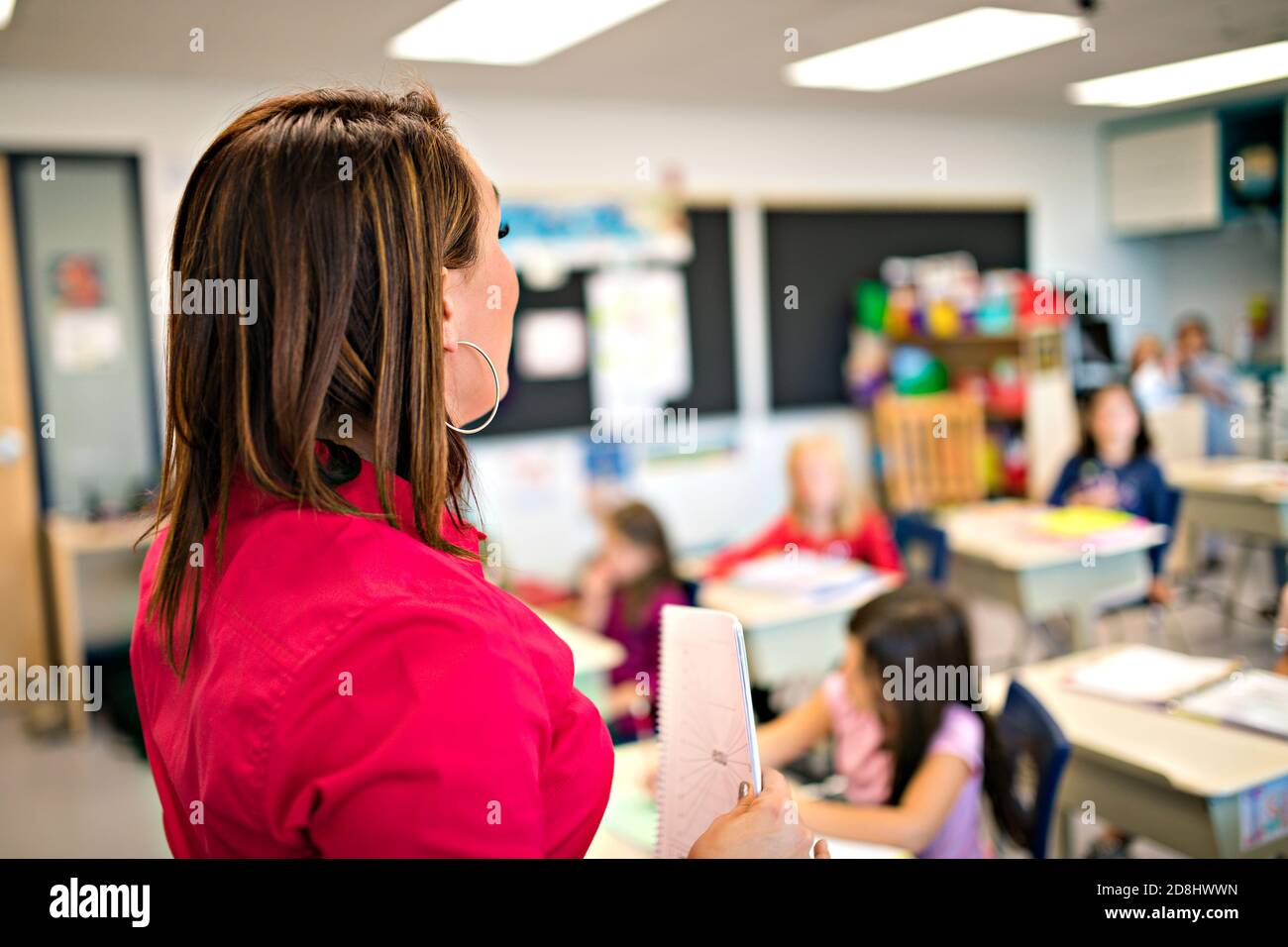 A Pretty teacher smiling at camera at back of classroom at the ...