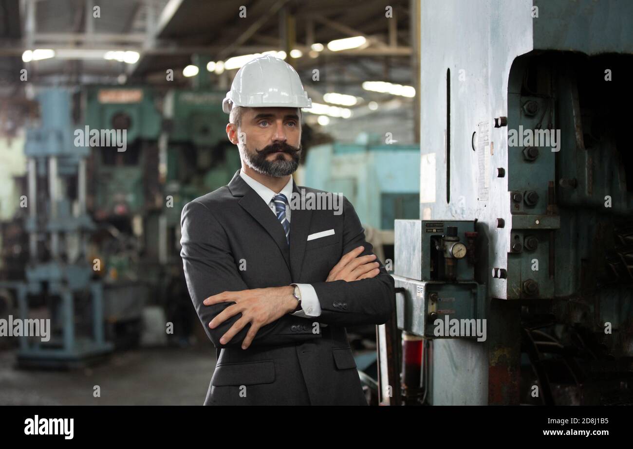 The bearded hipster director with engineer hat standing against cnc ...