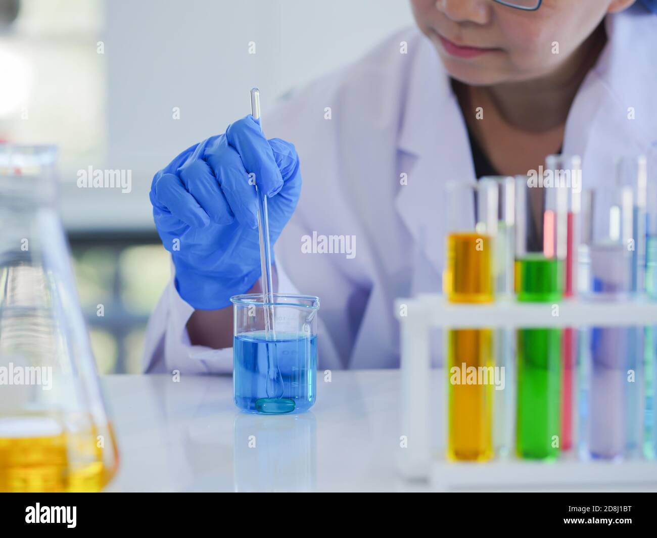 Senior female scientists are mixing liquid solution in a beaker for ...