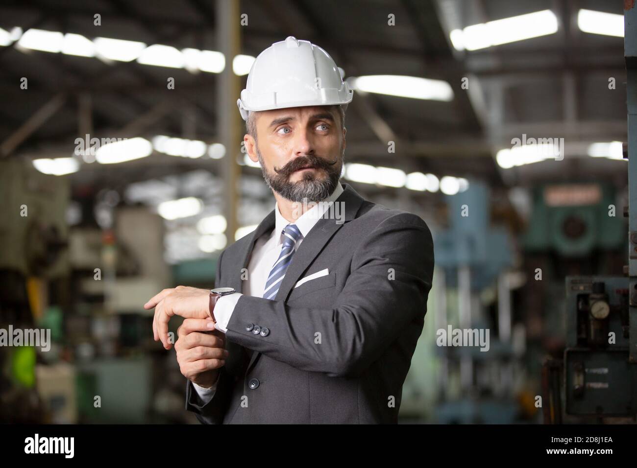 The bearded hipster director with engineer hat standing against cnc ...