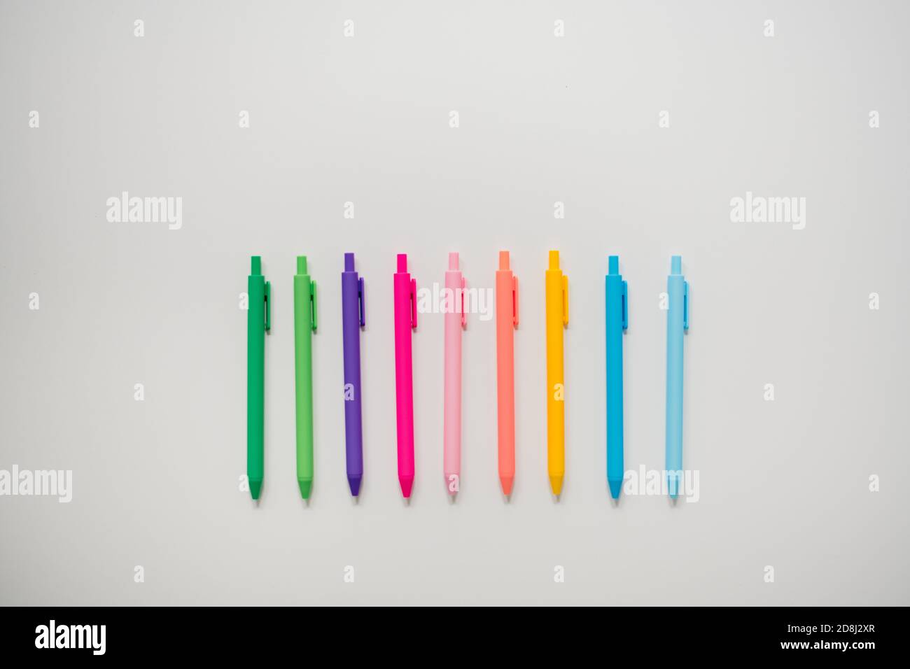 colorful pens lined up on plain white table Stock Photo - Alamy