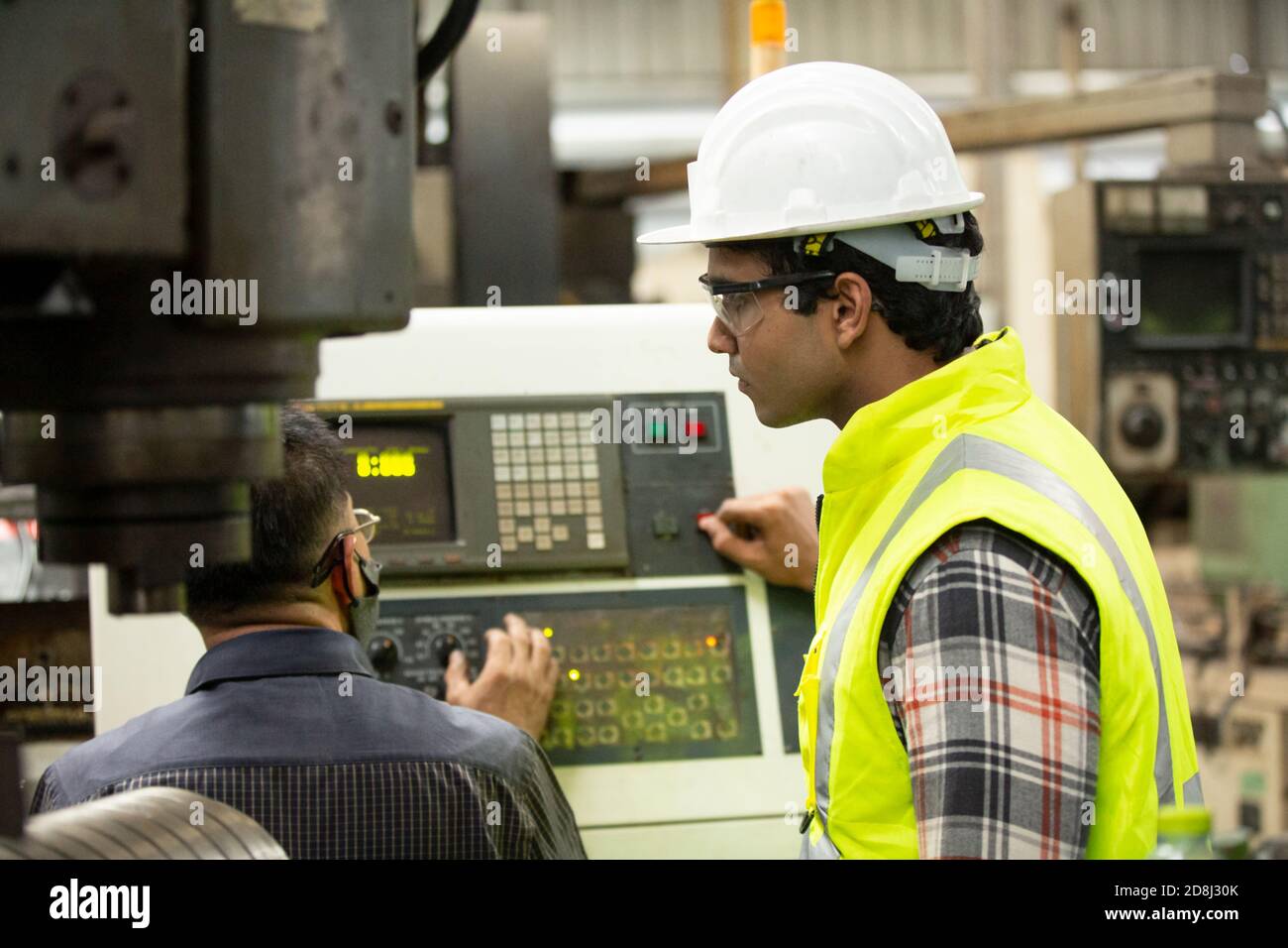 Engineers operating a cnc machine in factory Stock Photo - Alamy