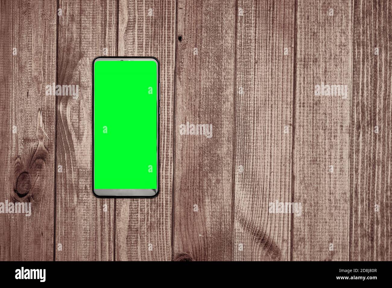 Mobile phone with green screen on empty wooden plank table. Blank ...