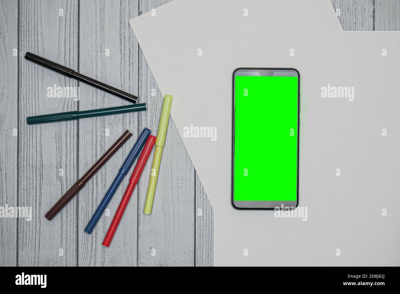 cell phone with green screen with felt-tip pens and white sheets on a ...