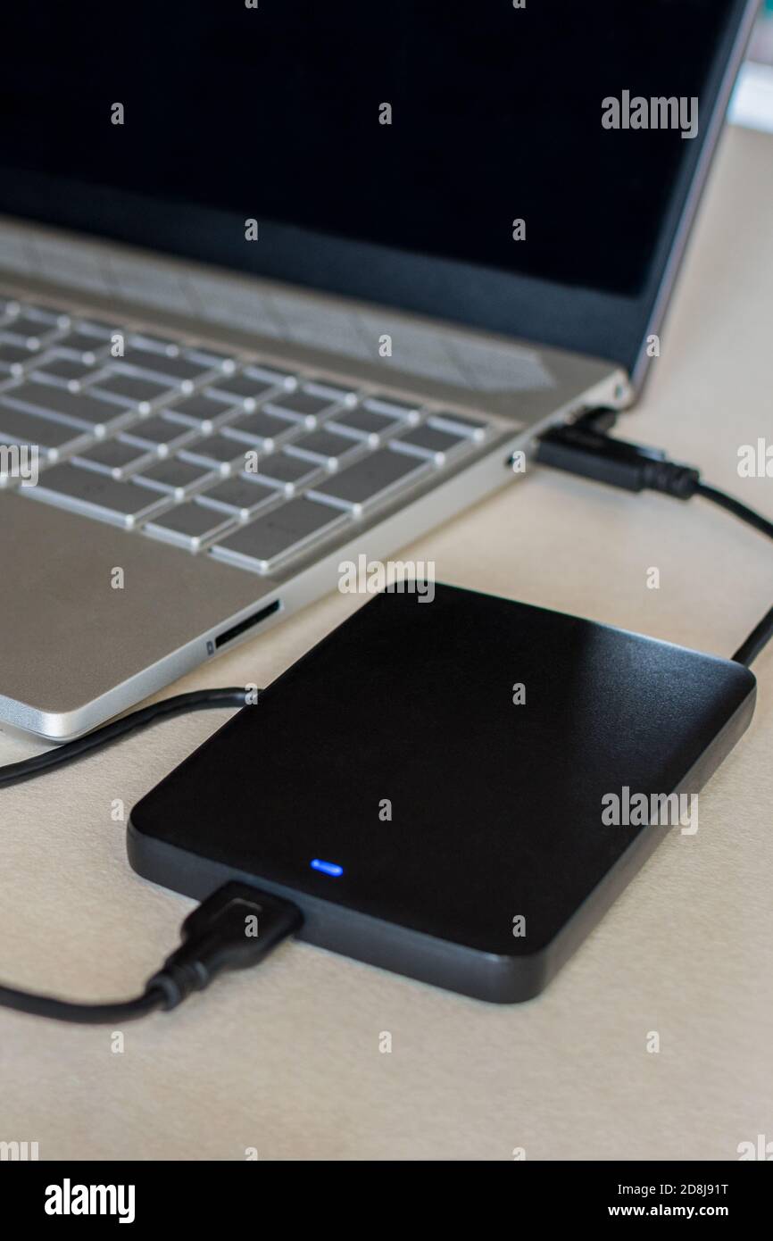 Vertical shot of portable hard drive connected to a laptop - concept of ...