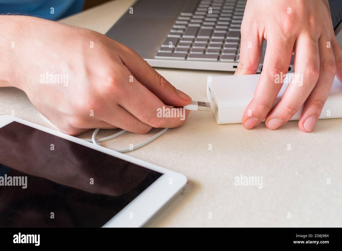 Power bank charging a tablet on desk Stock Photo - Alamy