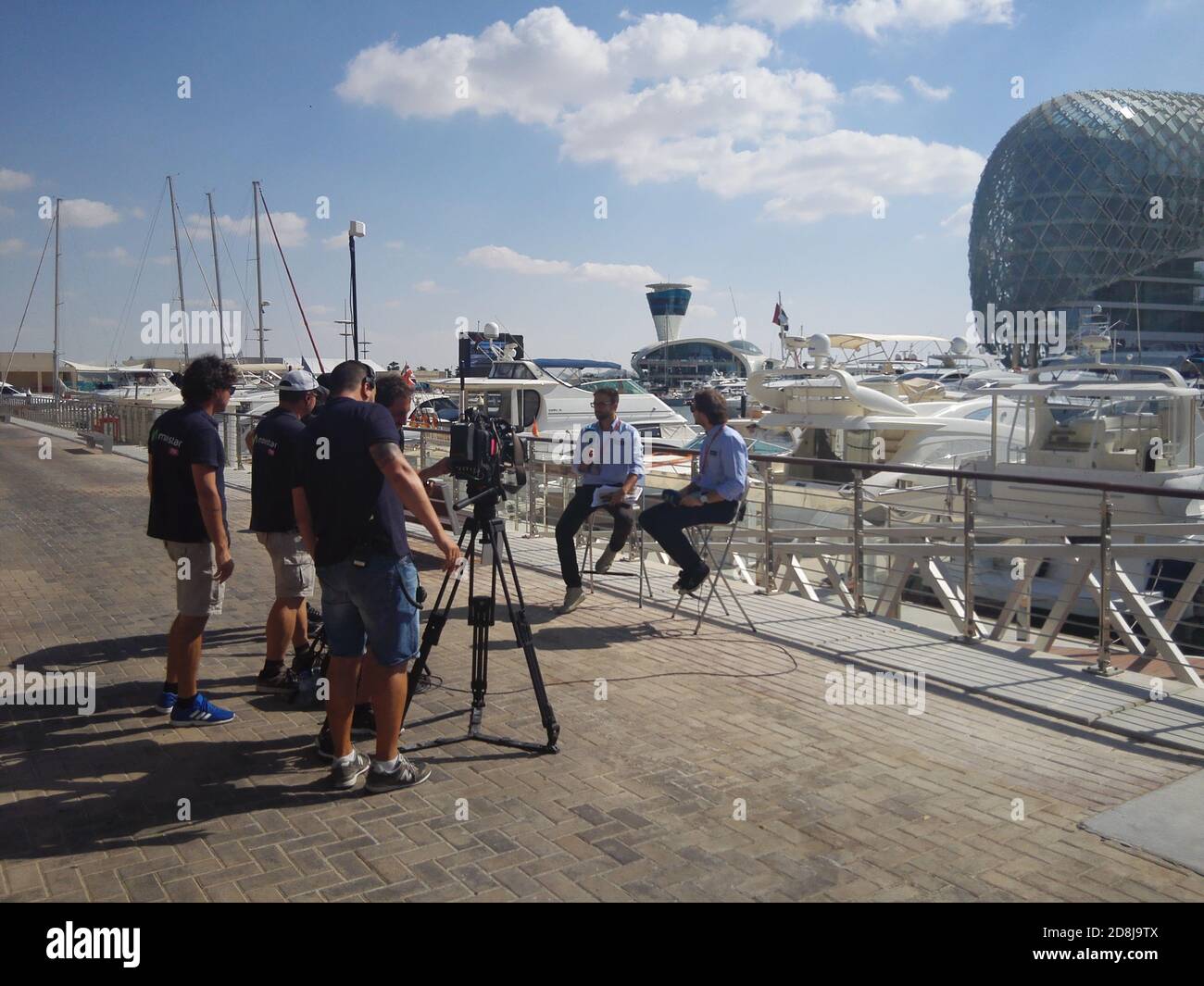 Camera crew filming interview with a view of the yas marina harbor ...