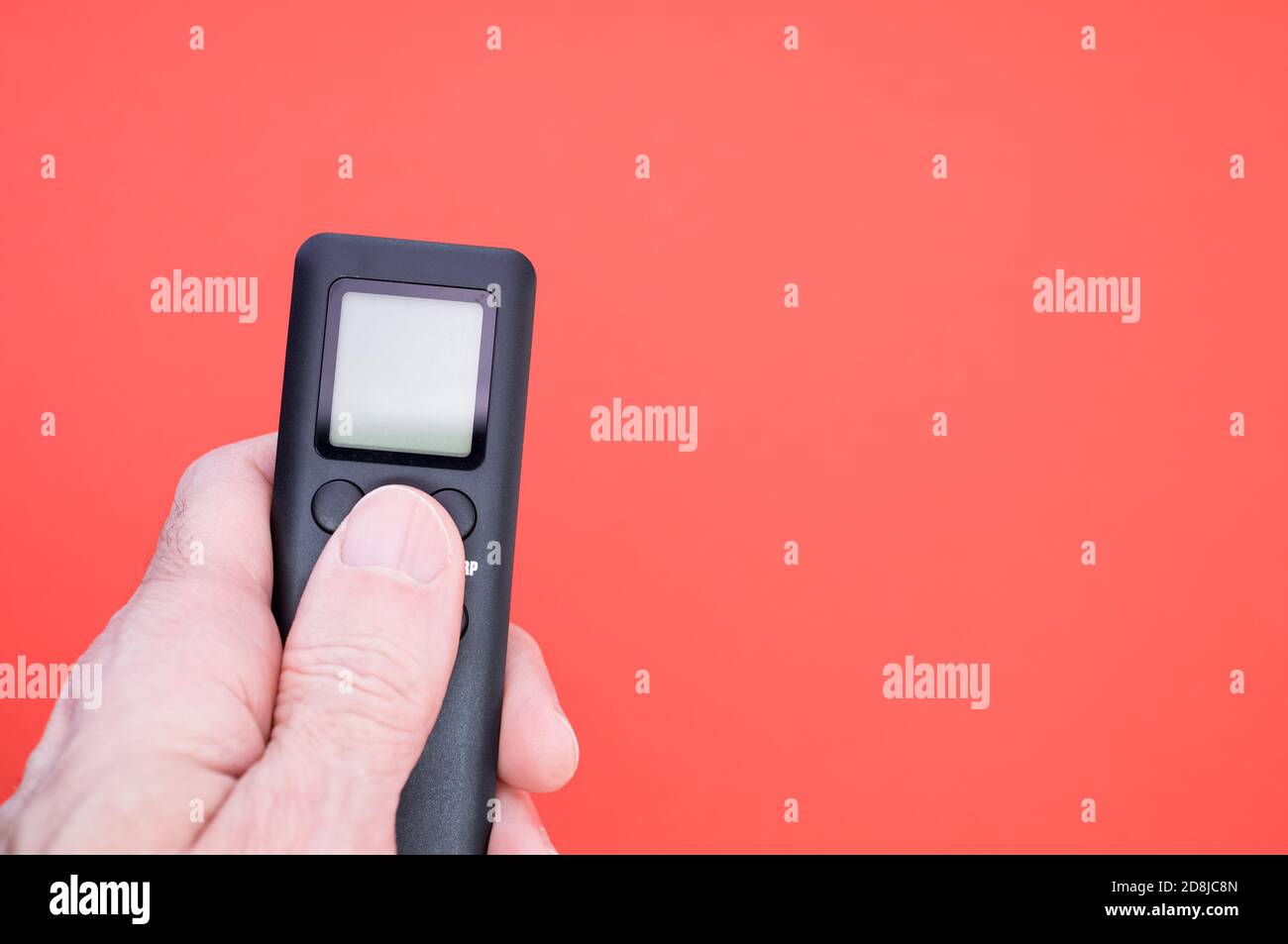 Male hand holding a black remote controller on red background Stock ...