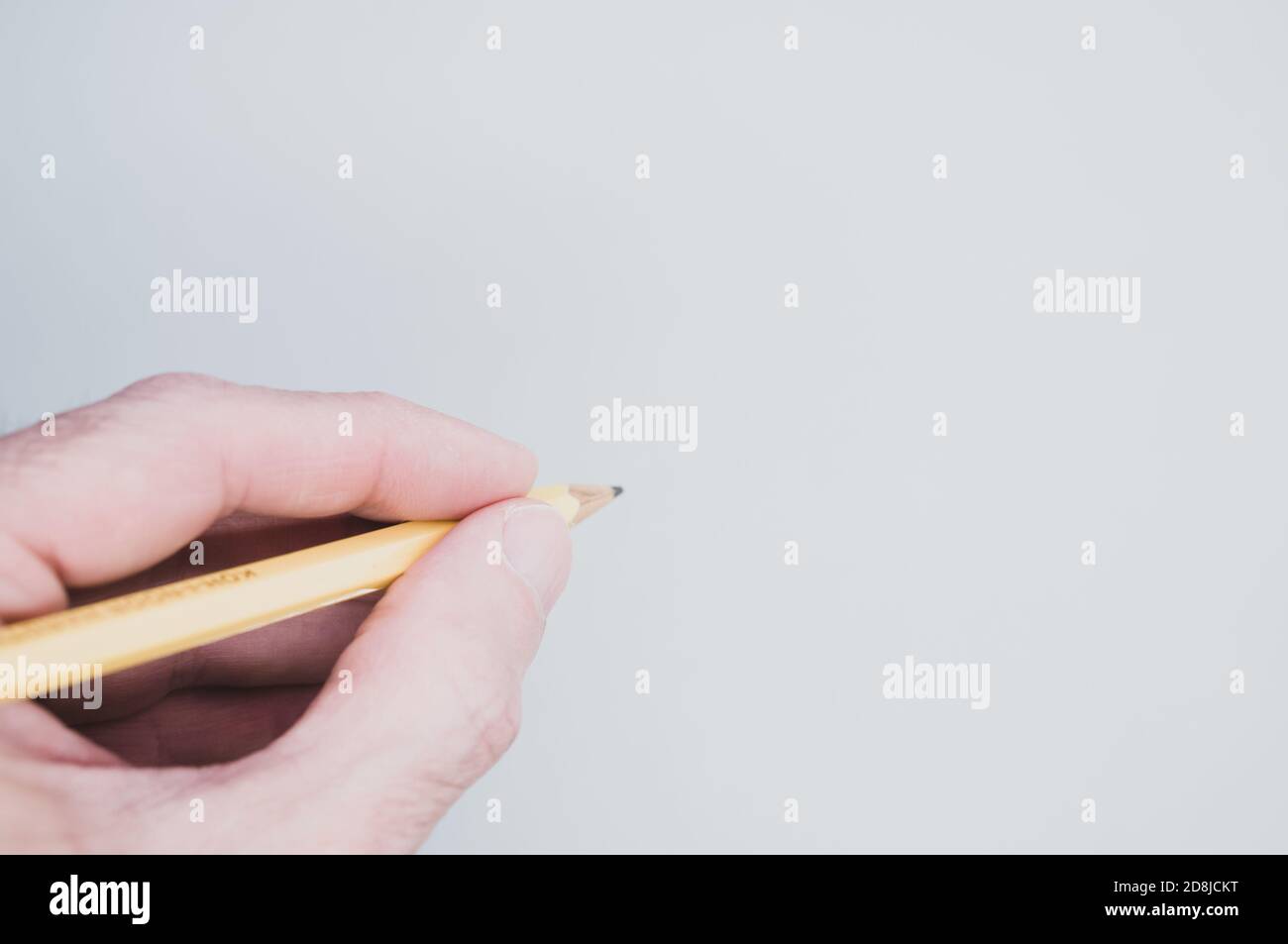 Hand holding a pencil on gray background for a copy space Stock Photo ...