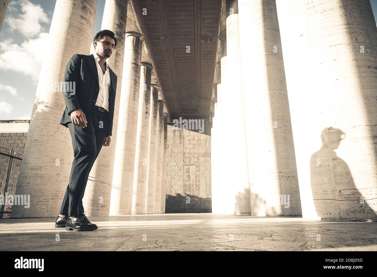 Elegant dressed man with down look walking outdoors near ancient ...
