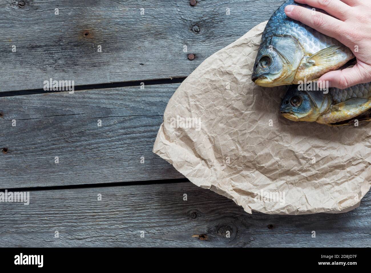 Hand holds Dried Volga bream vobla in a crumpled kraft paper roll Stock ...