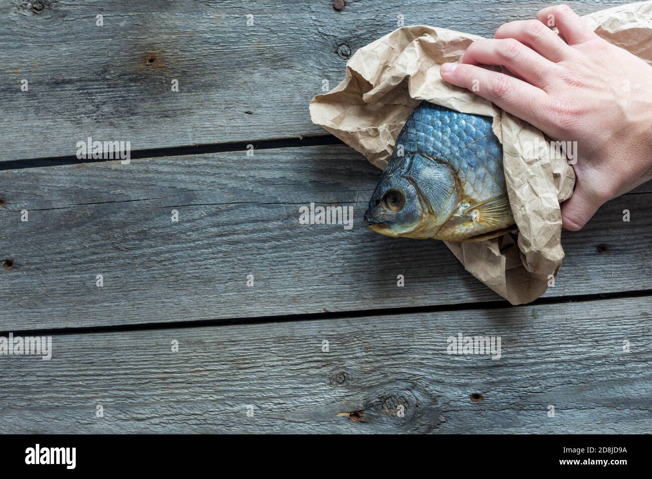 Hand holds Dried Volga bream vobla in a crumpled kraft paper roll Stock ...