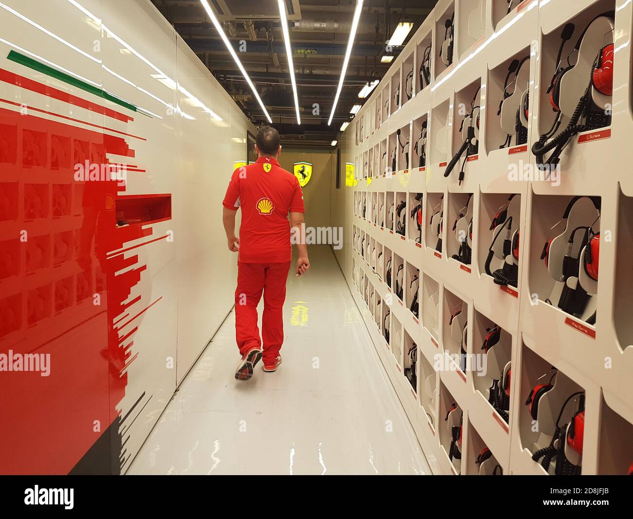 The staff member wearing red and seen from the back, walks through the ...