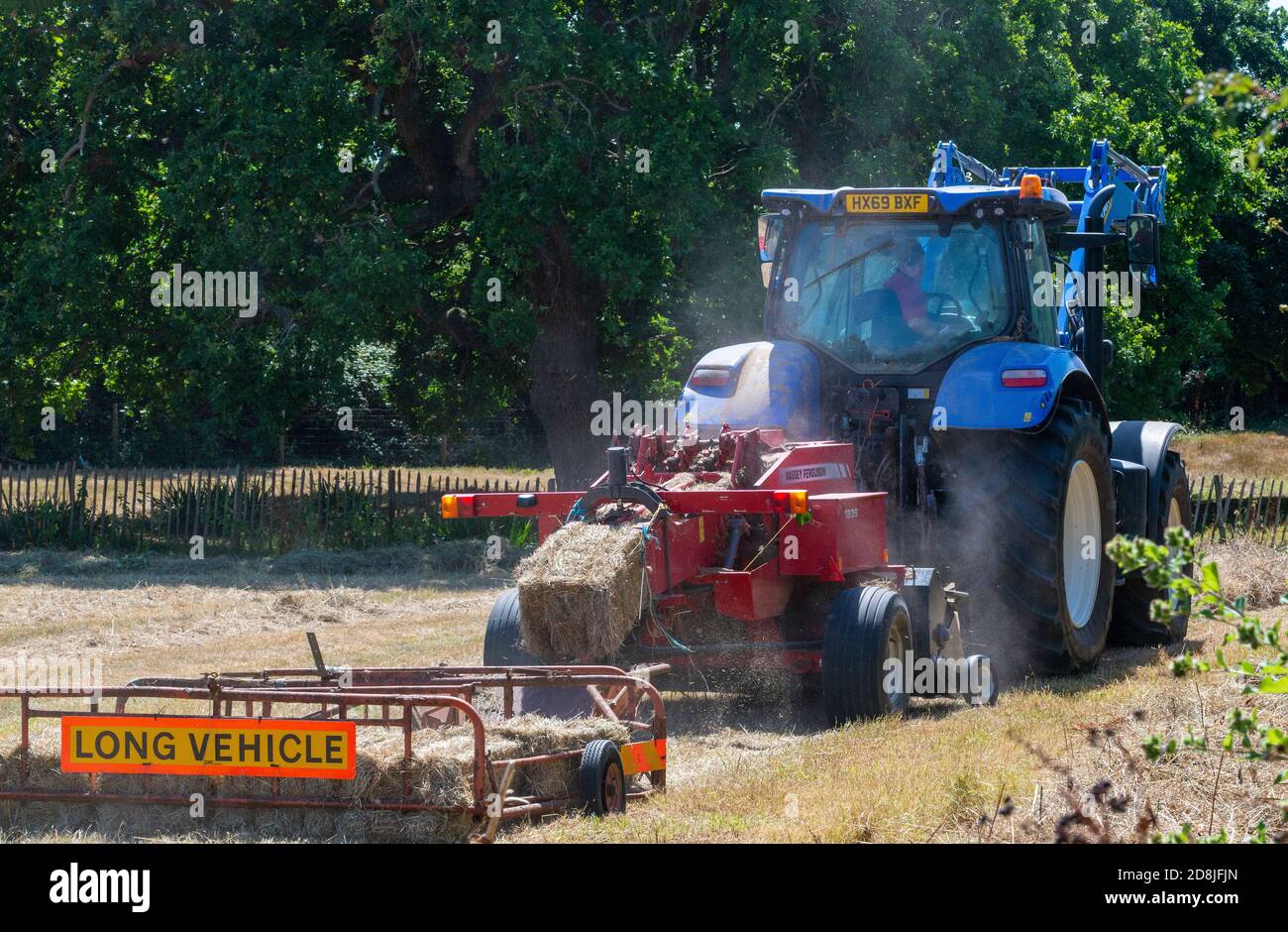 Farmer in summer with tractor and trailer making hay in field in West ...