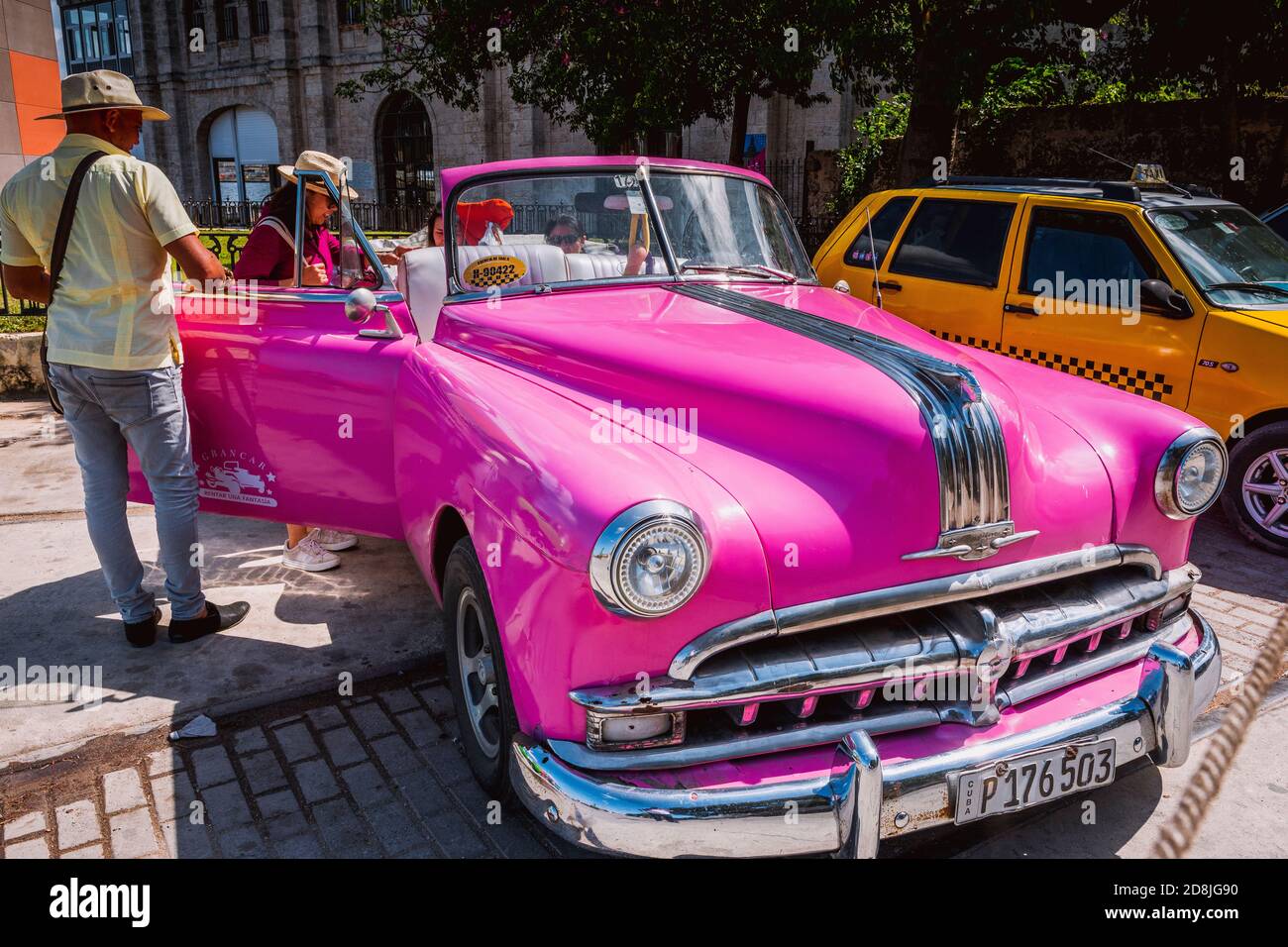 A Cuban taxi driver helps raise some Asian tourists a vintage taxi ...