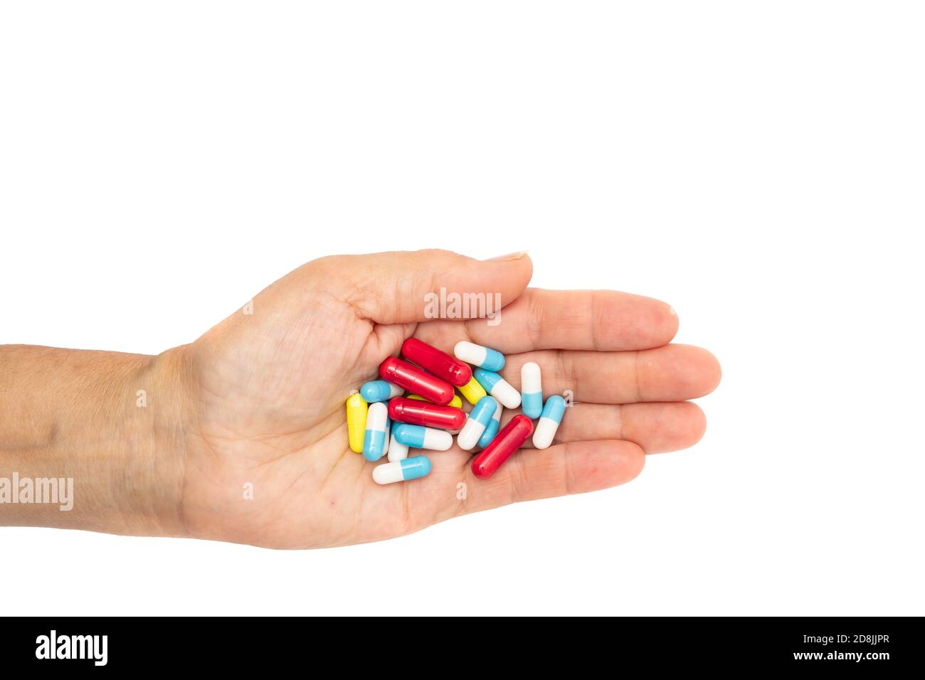 A female hand with multiple colors pills on white background, concept ...